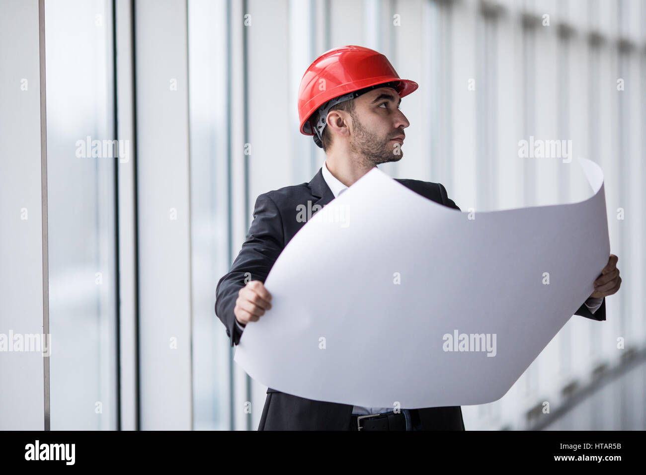 Portrait of an architect builder studying layout plan of the building ...