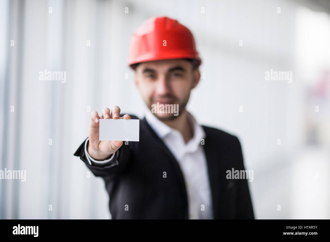 Construction worker holding blank business card, in building ...