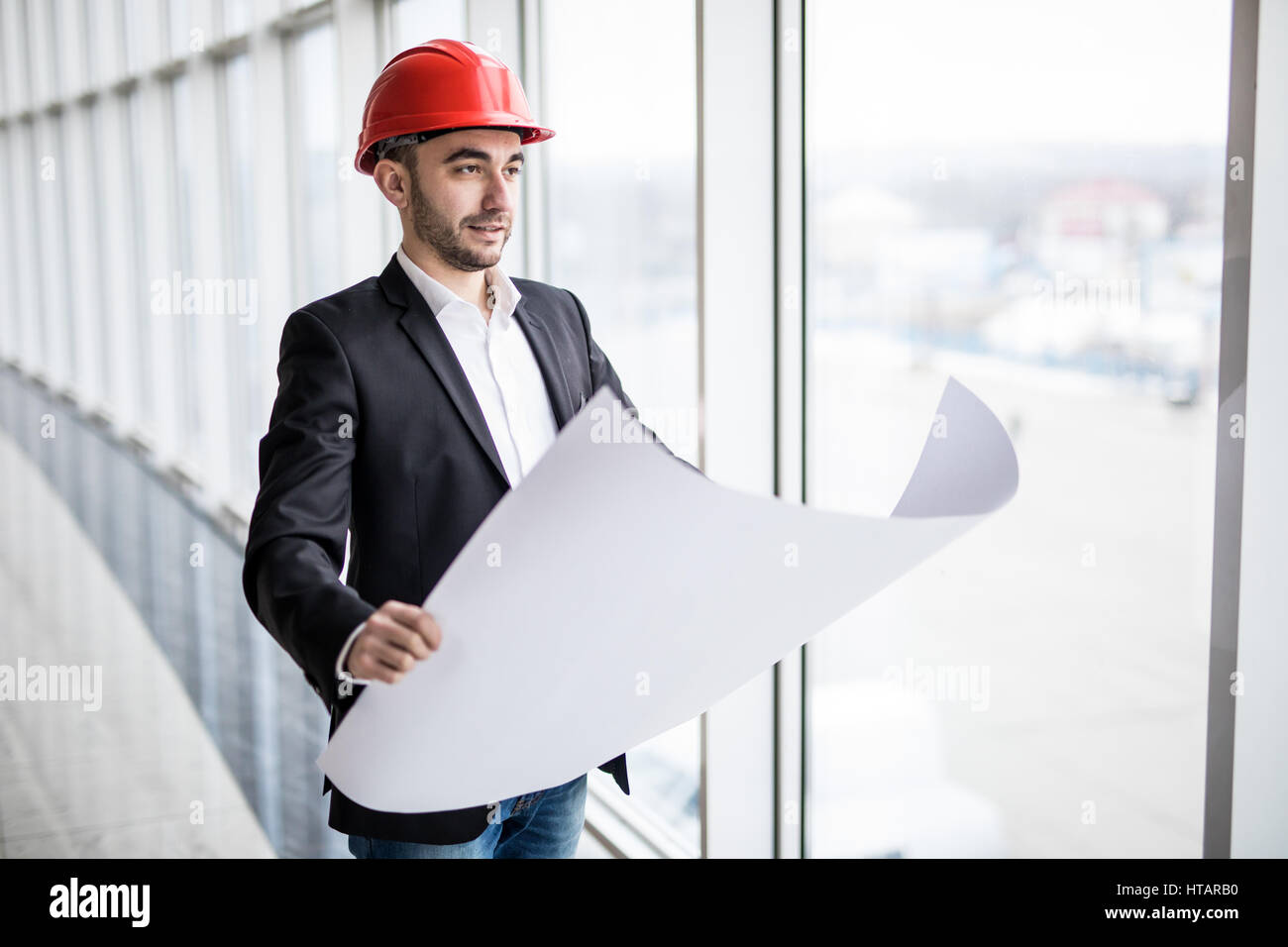 Male architect looking at blueprints against white background Stock ...