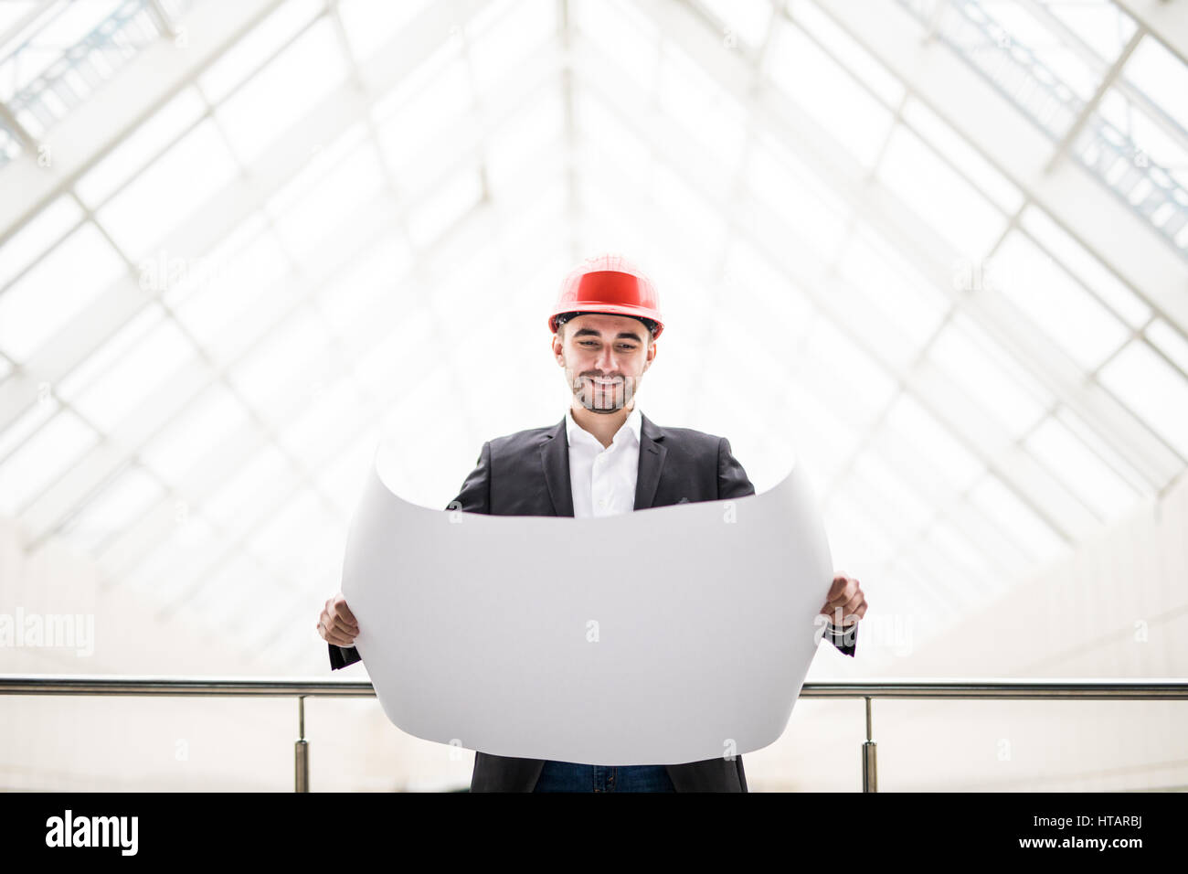 Male architect looking at blueprints against white background Stock ...