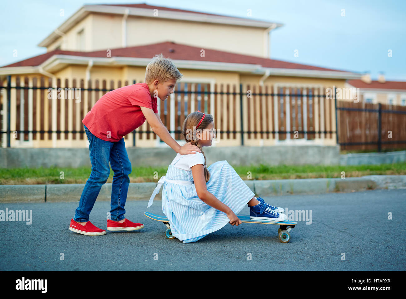 Portrait of boy and girl playing in the street: boy pushing her sister ...