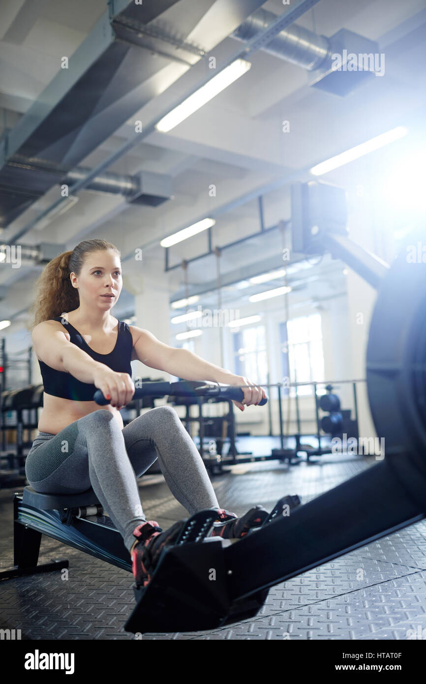 Young female sweating while rowing in gym Stock Photo - Alamy