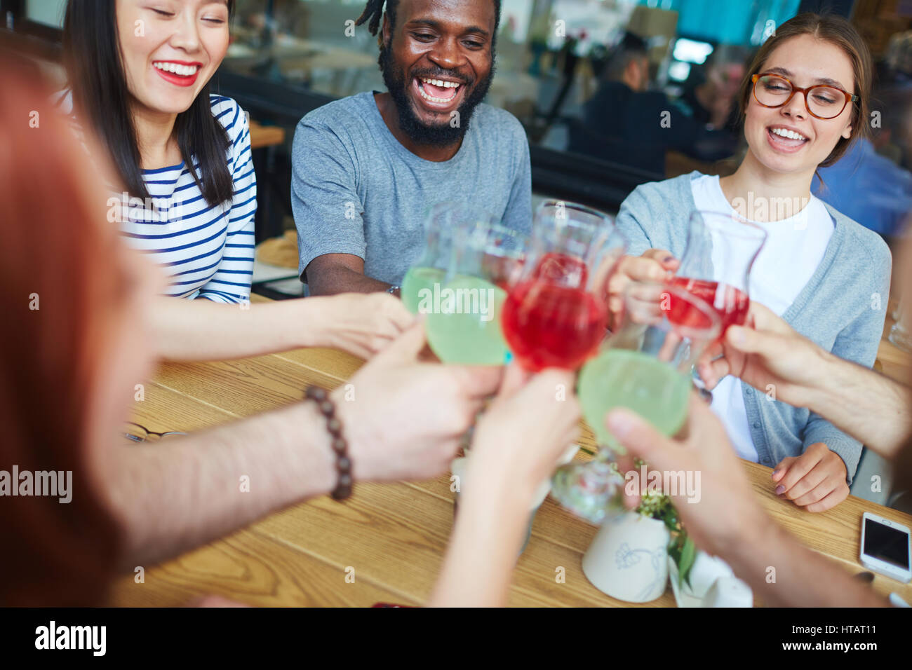 Multi-ethnic group of young buddies cheering up with drinks Stock Photo ...