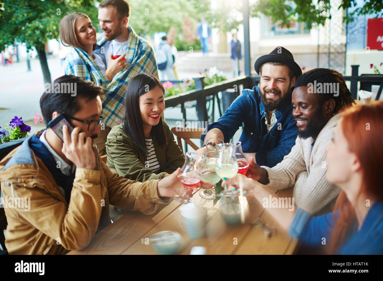 Youthful friends toasting with drinks during hangout Stock Photo - Alamy