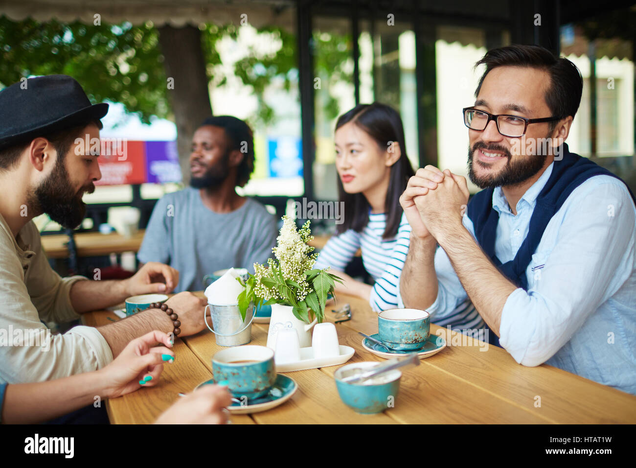 Restful guys and girl talking by cup of tea Stock Photo - Alamy