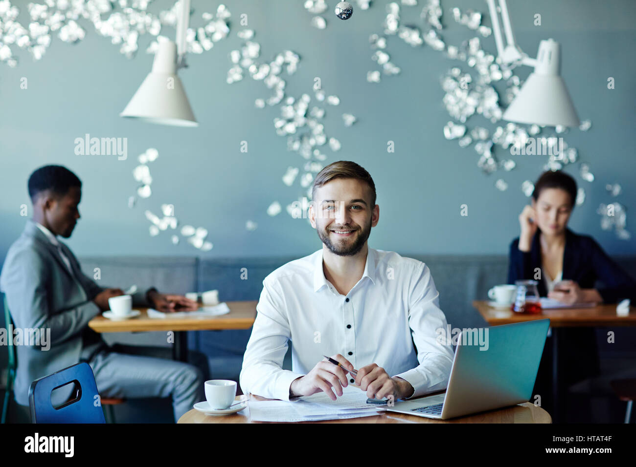 Young successful economist working with papers while sitting in cafe ...