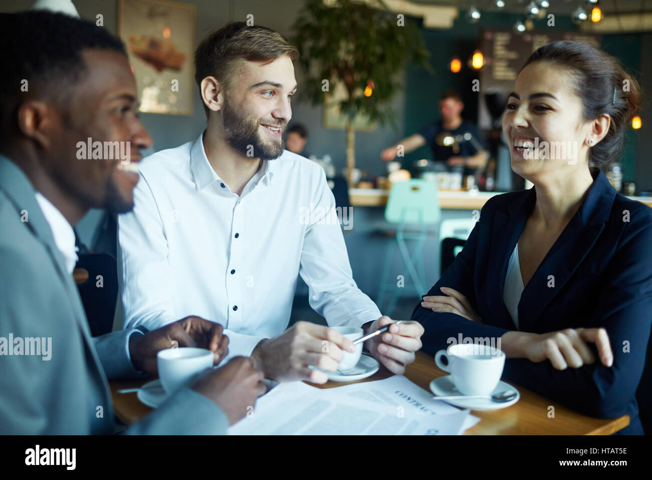 Cheerful co-workers having curious conversation during coffee-break ...