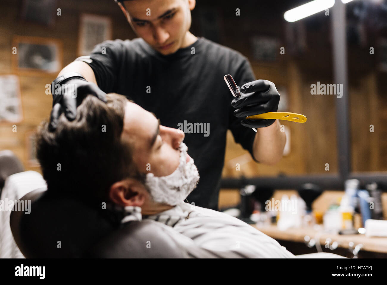 Skilled barber shaving young man Stock Photo - Alamy