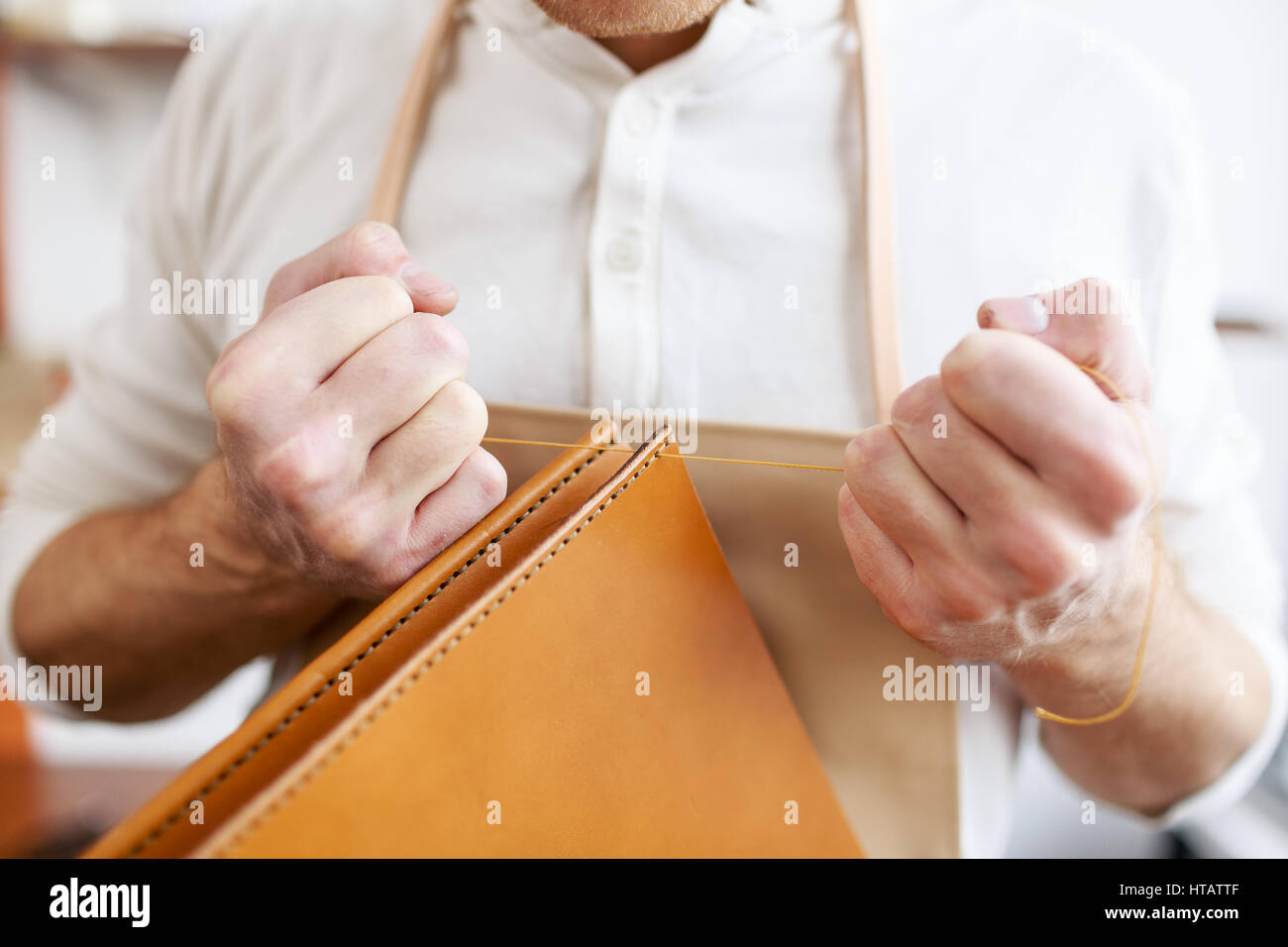 Tanner tying threads on ends of leather briefcase Stock Photo - Alamy