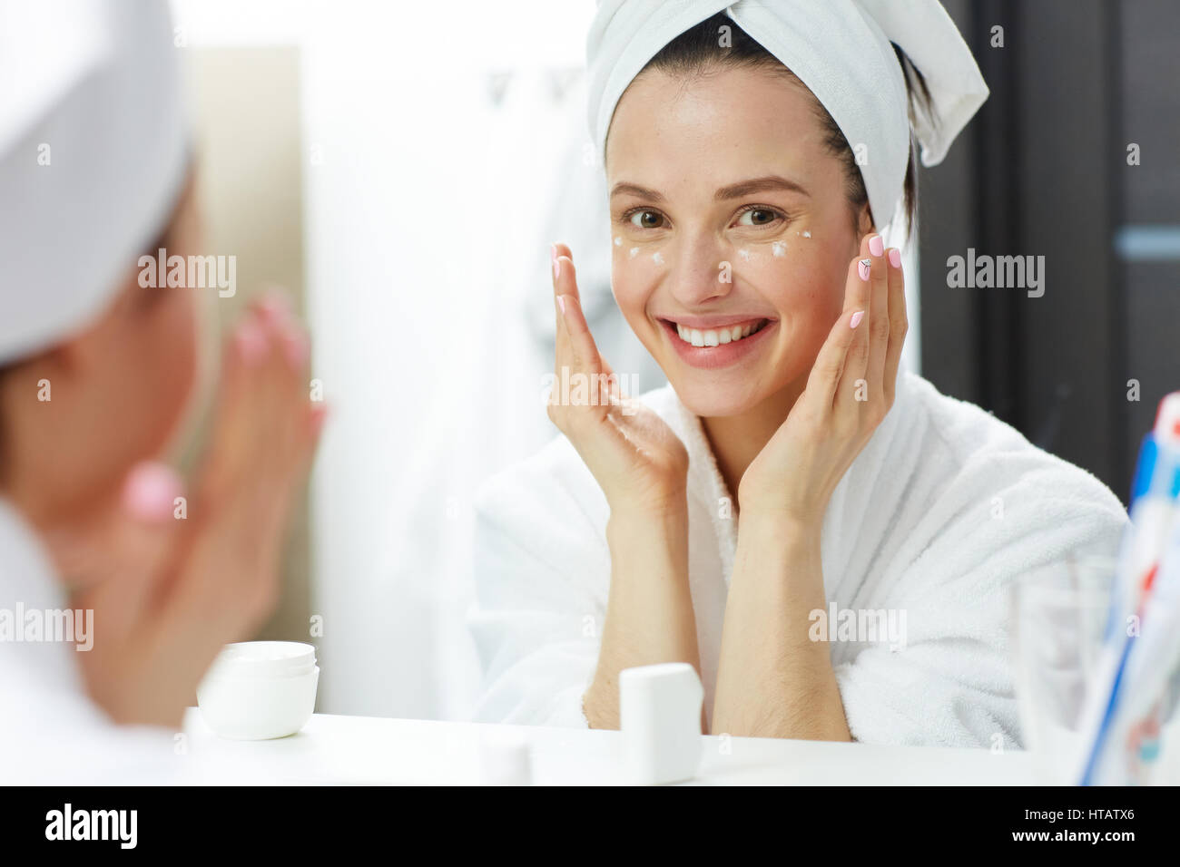 Happy woman with toothy smile pampering eye-cream Stock Photo - Alamy