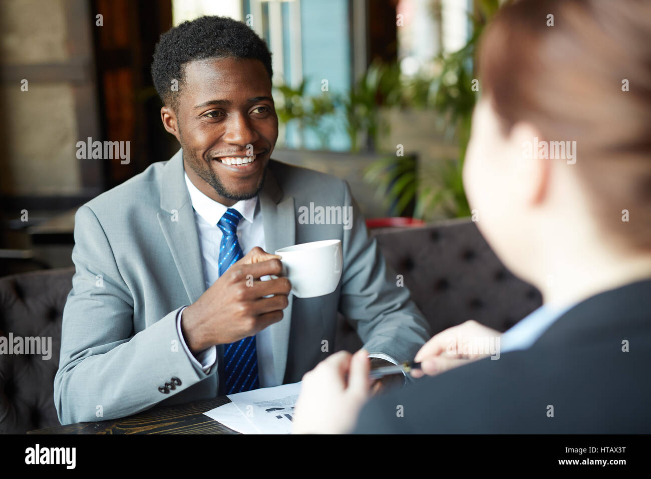Two business people meeting in modern cafe: African-American man ...