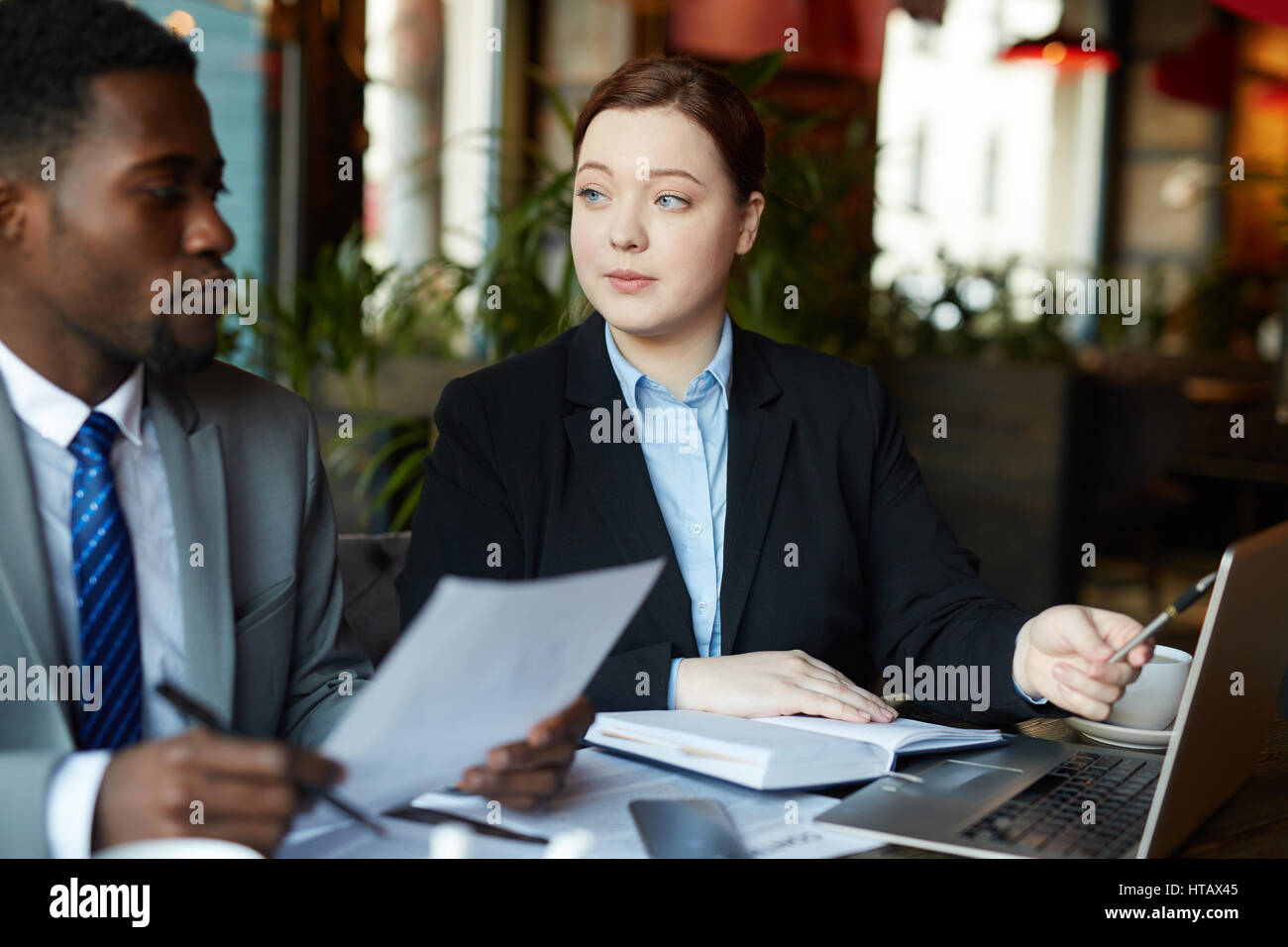 Two business people meeting in modern cafe: Young professional woman ...
