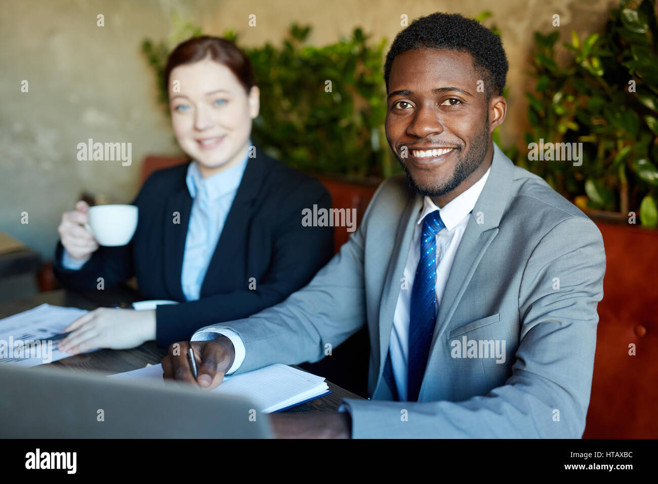 Two business people during work meeting in modern cafe: Handsome African-American businessman ...