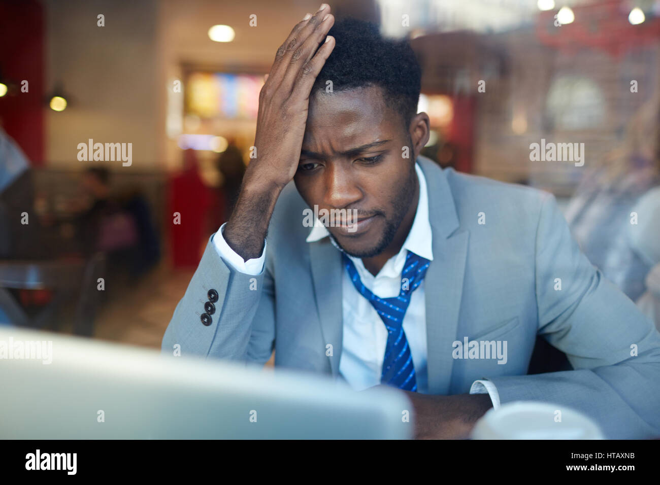 Businessman looking upset and resting his head on hand while sitting at ...