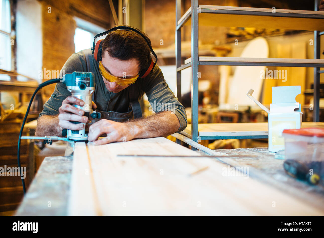 Professional joiner with wood-router cutting wooden plank Stock Photo ...