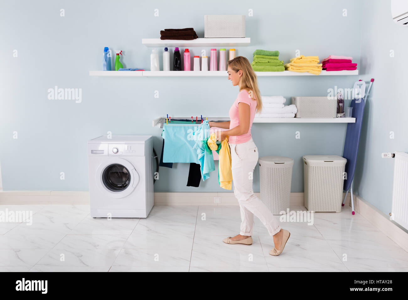 Happy Woman Washing Stained Clothes In Washing Machine In Utility Room ...