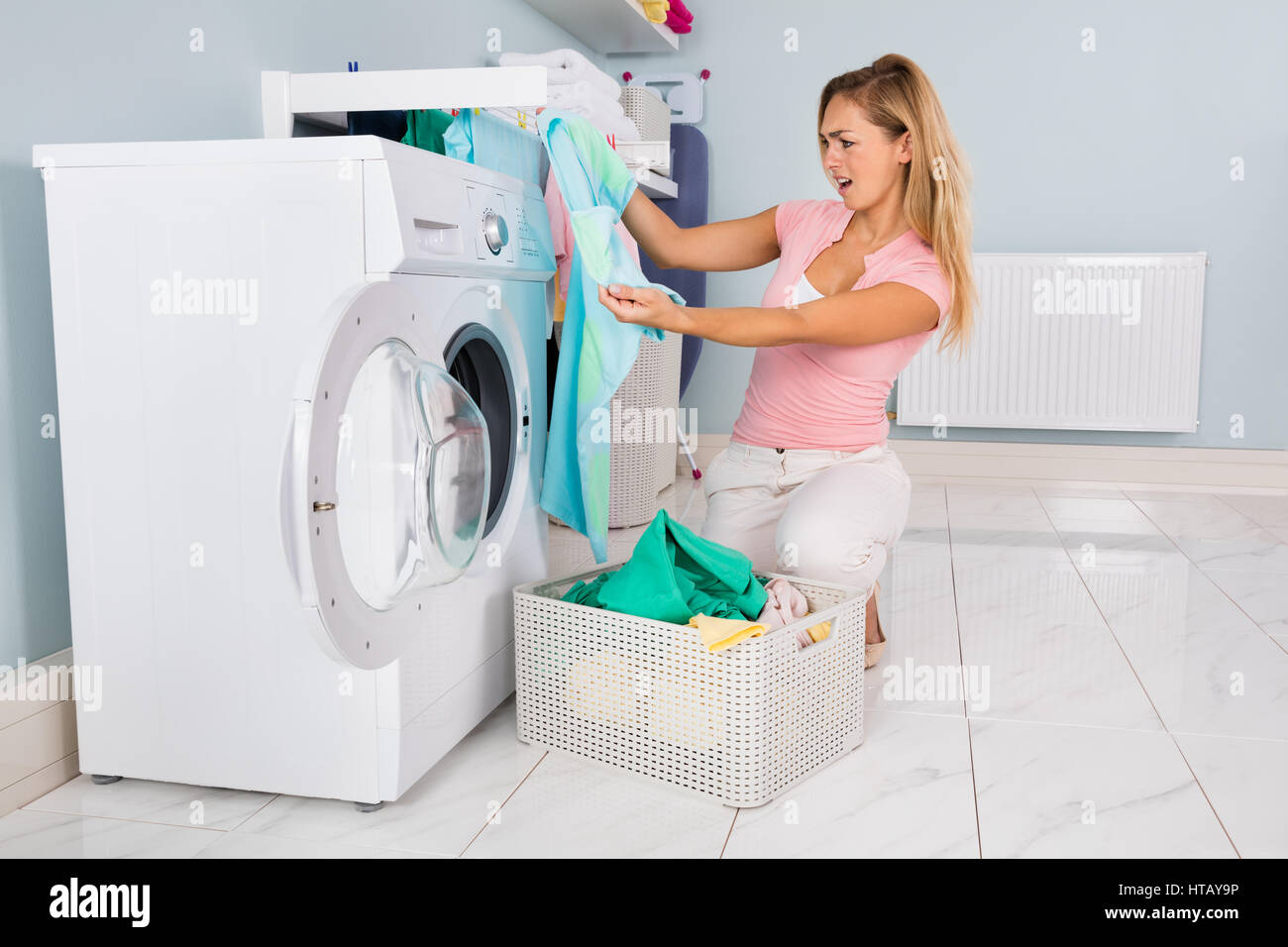 Young Woman Looking At Clothes After Washing In Washing Machine At ...