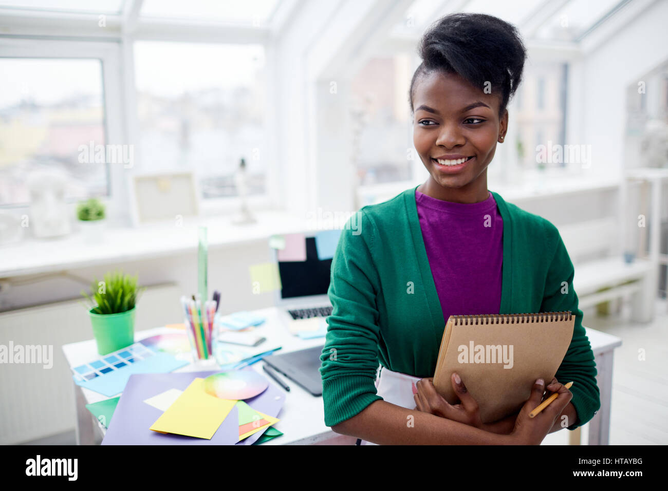 Smiling girl with notepad in studio of design Stock Photo - Alamy