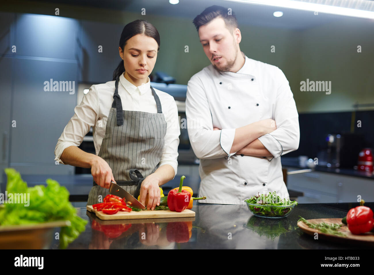 Professional chef and his trainee cooking fresh vegetable salad Stock ...