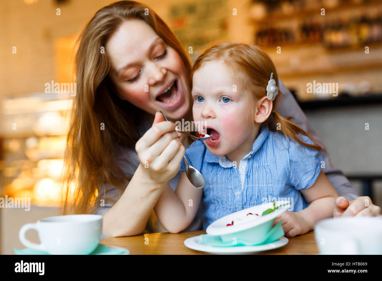 Woman feeding her daughter with sweet dessert Stock Photo - Alamy