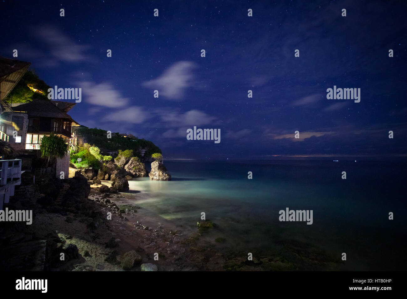 Night landscape in the mountain village on the ocean with lots of stars ...