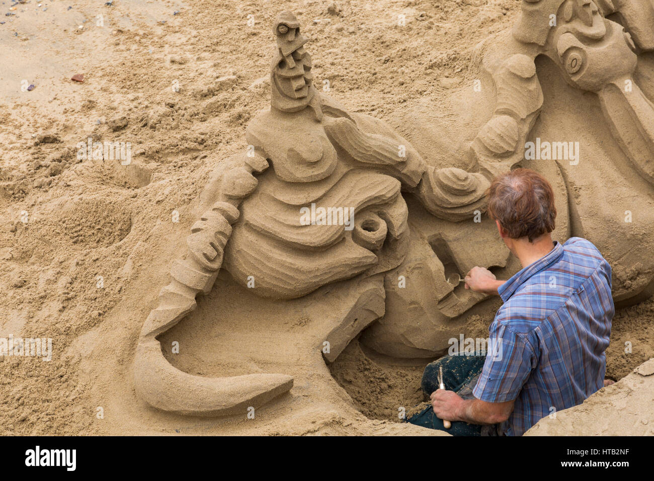 Man artist working on sand sculptures by the side of the River Thames ...