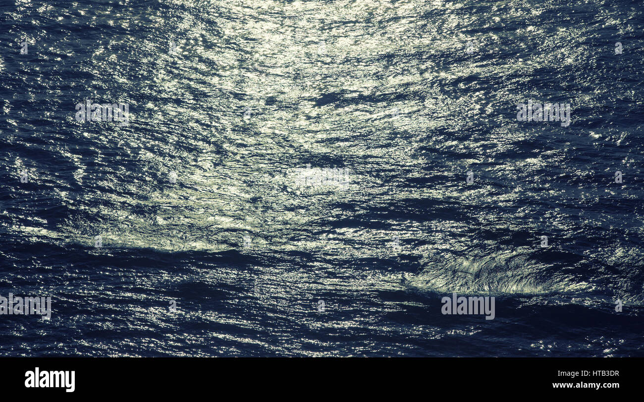 Ocean waves and the water surface at sunset with the reflection of the ...