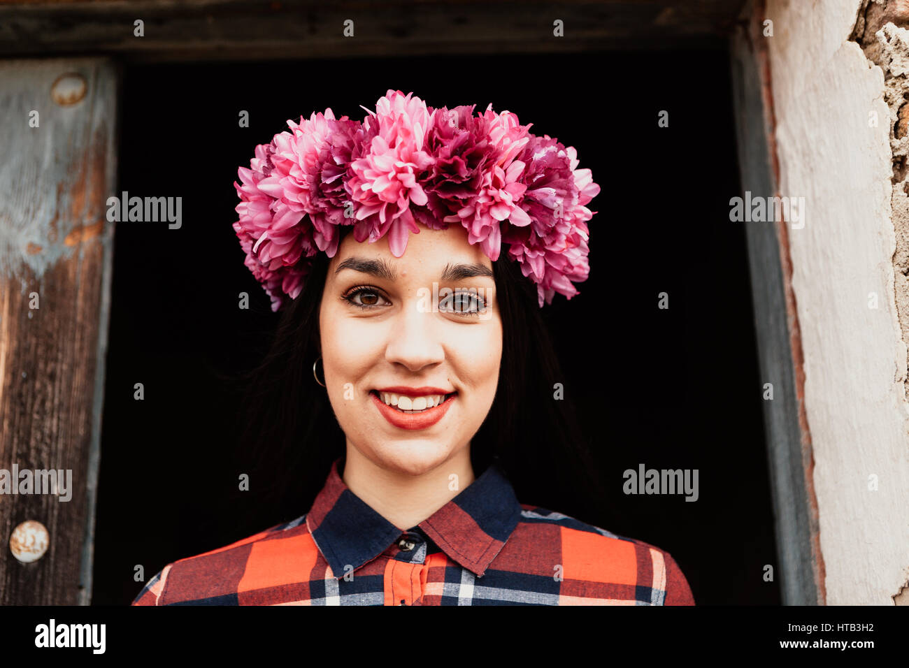 Pretty girl with pink flower crown in her head and a black background ...