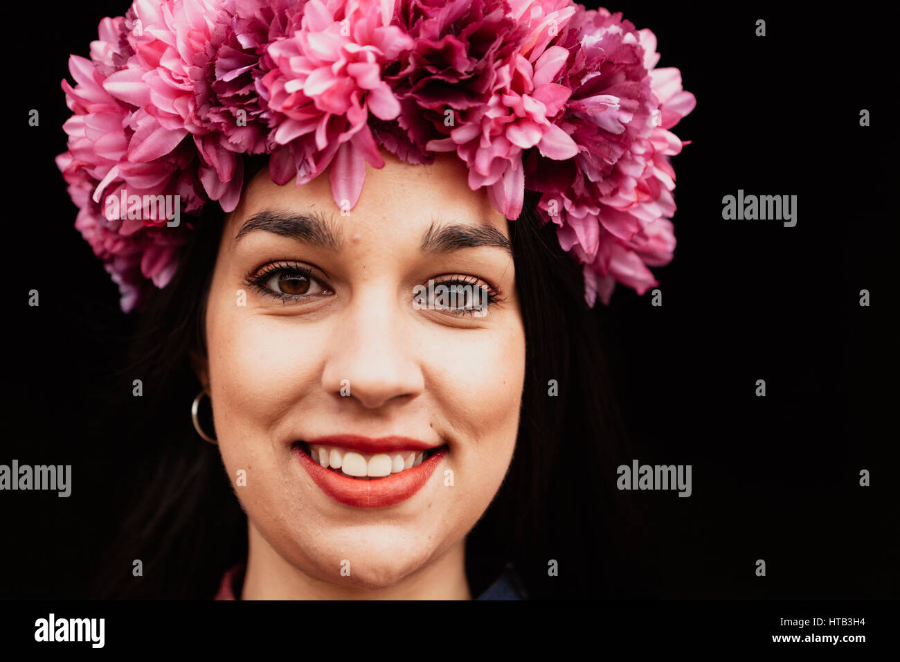 Pretty girl with pink flower crown in her head and a black background ...