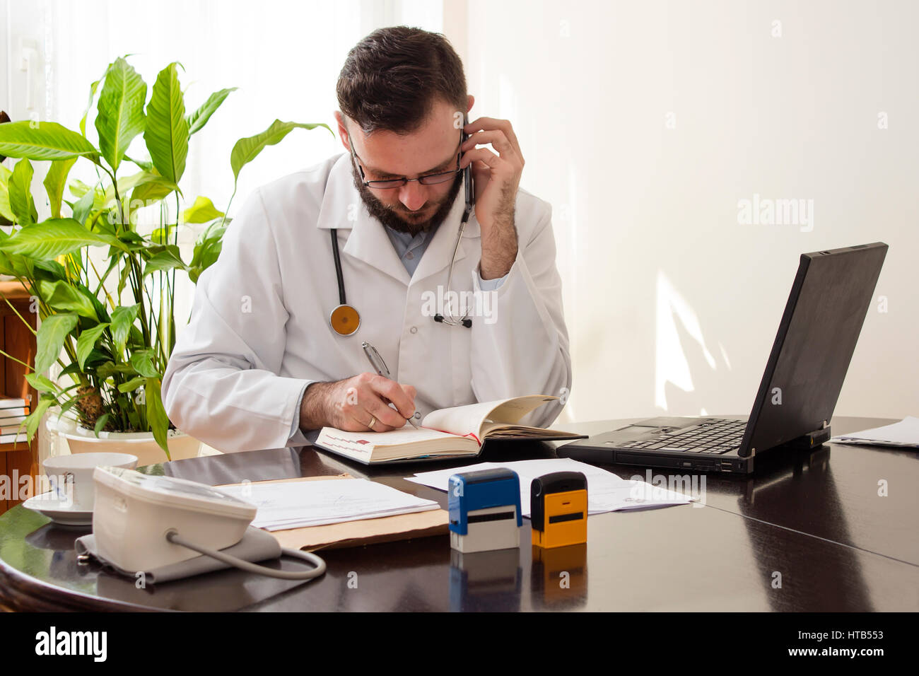 Doctor in the doctor's office talking on the phone and checks for ...