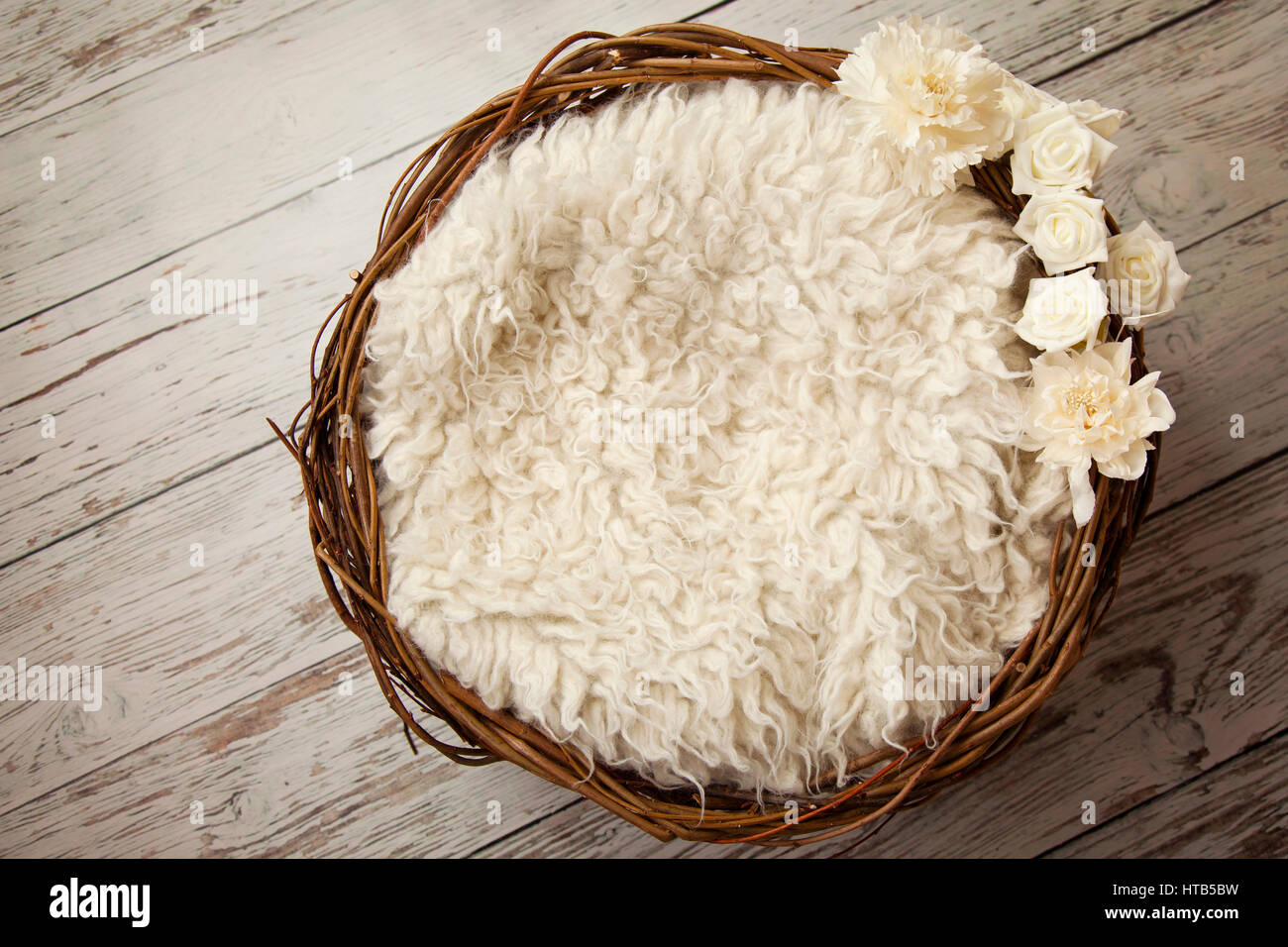 Empty basket filled with a flokati rug and flowers on the rim of the ...