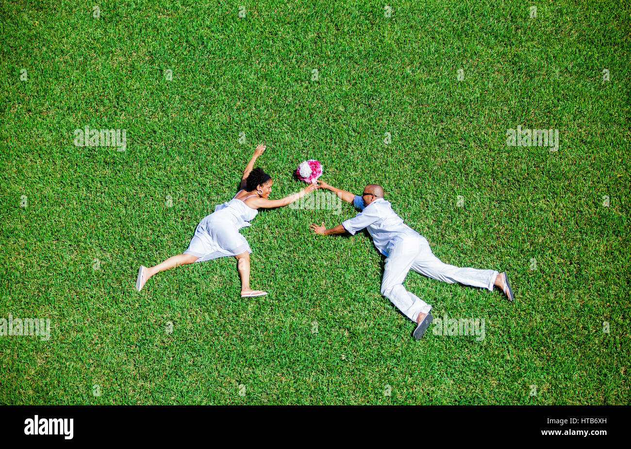 Couple reaching for a bouquet lying on grass Stock Photo - Alamy
