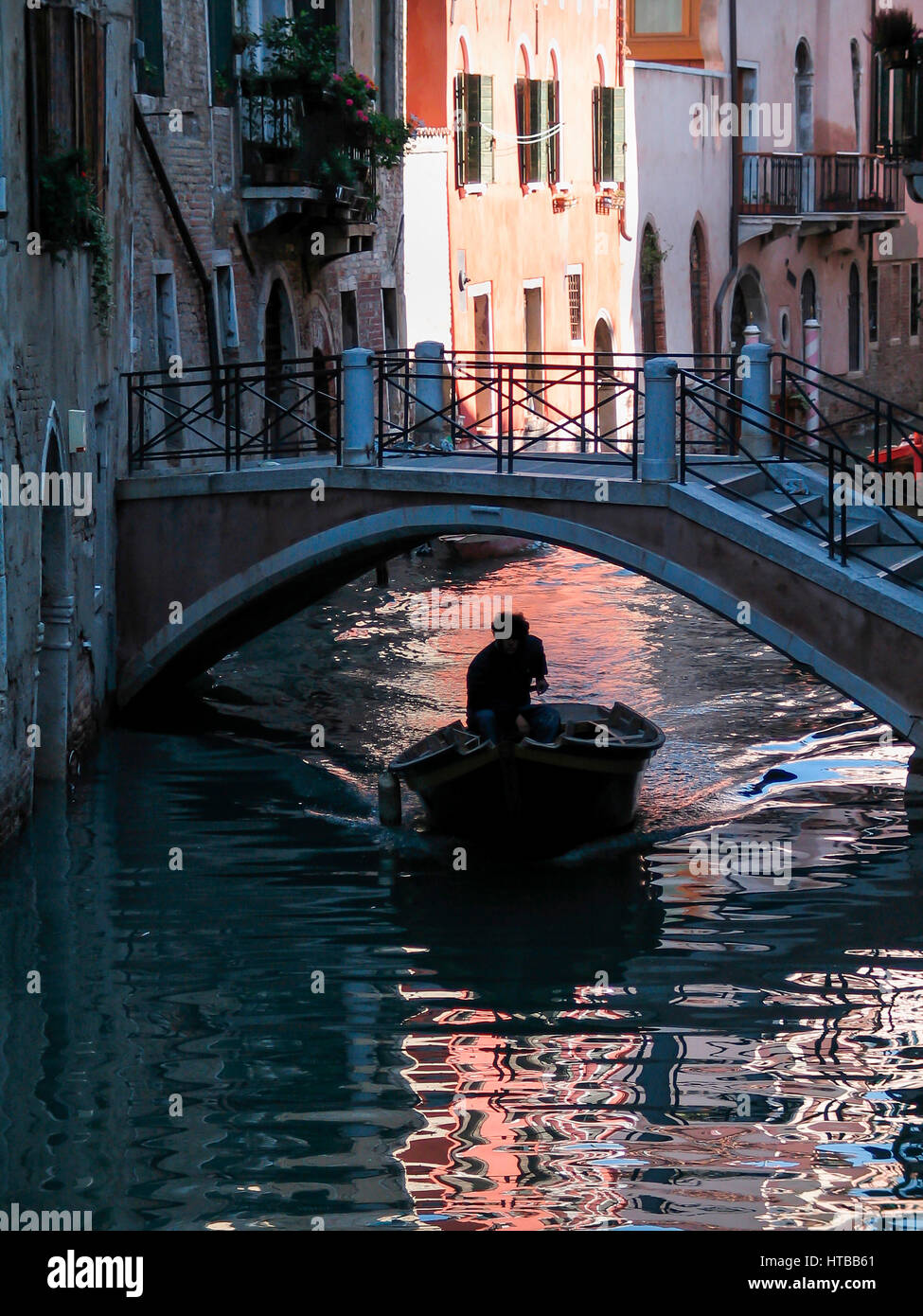 Beautiful canal view in Venice with a lone boat passing underneath an ...