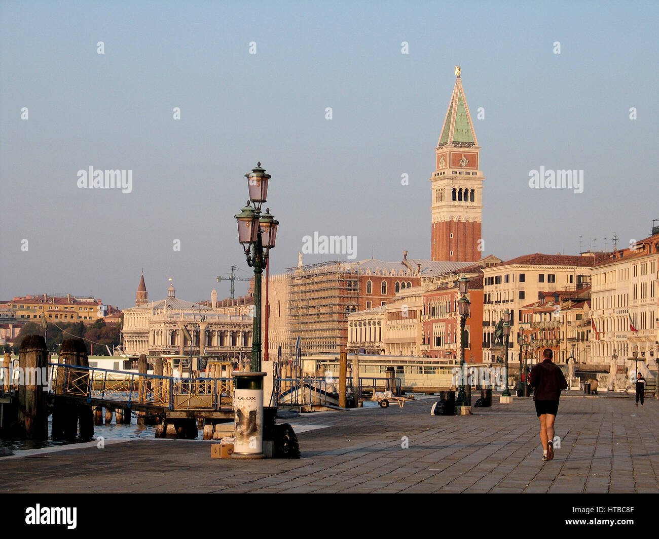 A lone figure walks along the tranquil waterfront of Venice during ...
