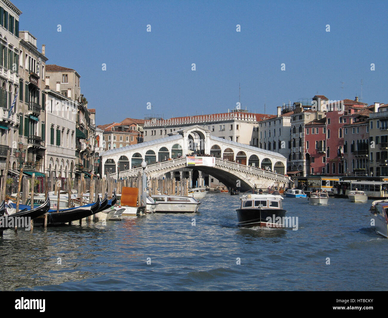 Rialto Bridge in Venice bustling with boats and visitors on a bright ...