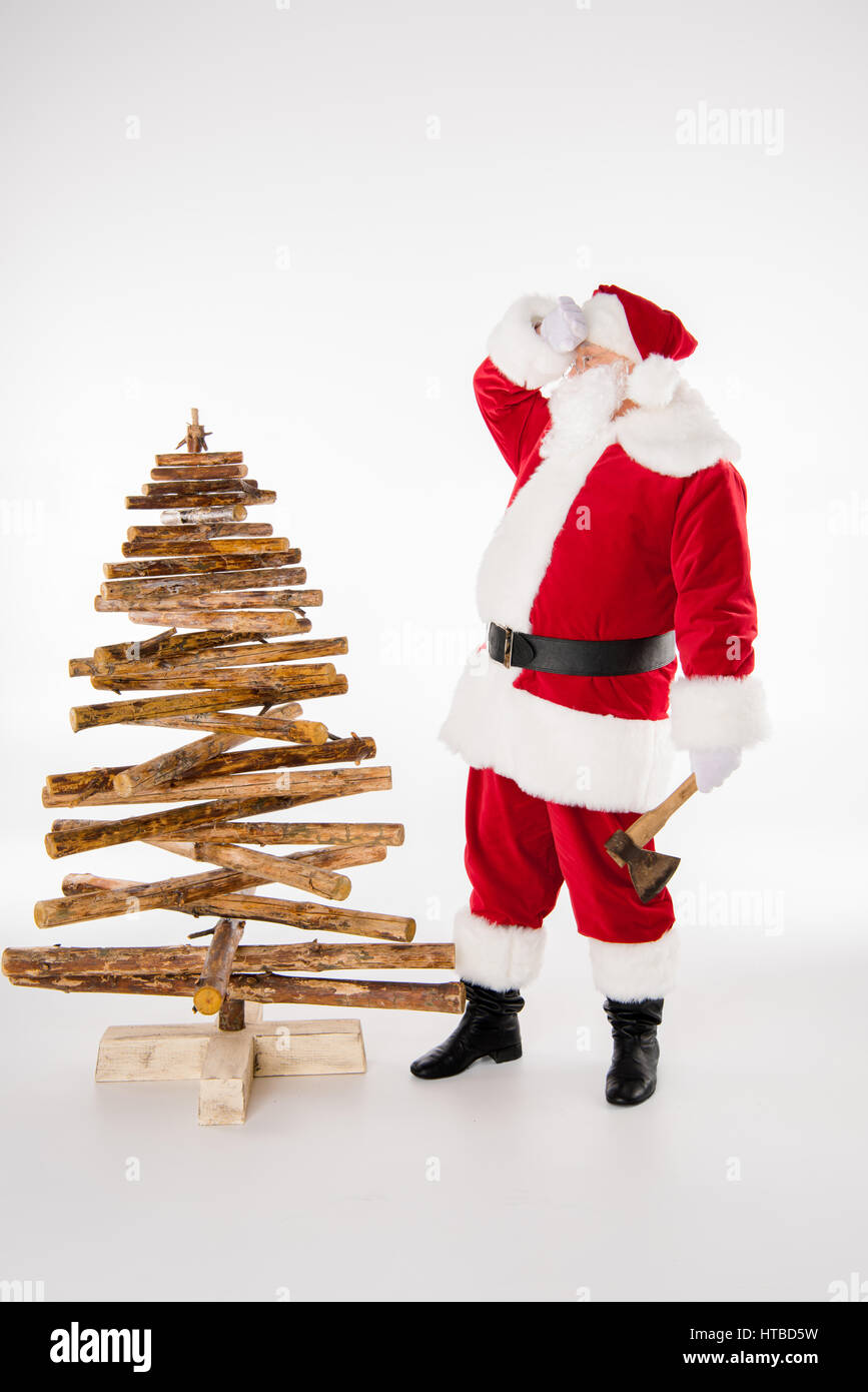 Tired Santa Claus making Christmas tree from firewood on white Stock ...