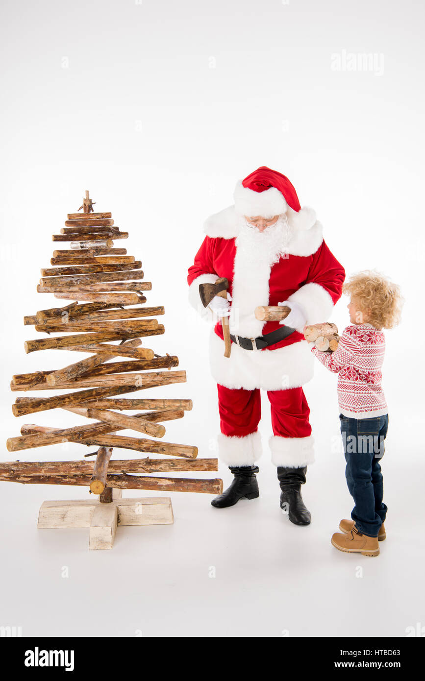 Santa Claus with kid creating Christmas tree from firewood on white ...