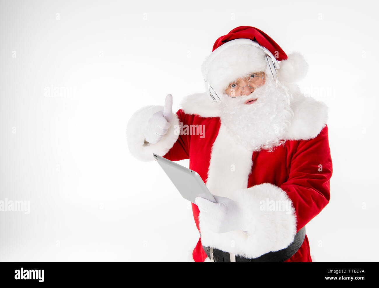 Happy Santa Claus listening music with headphones and using digital ...
