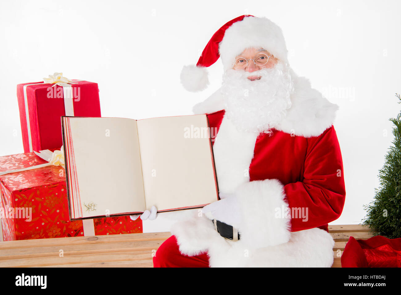 Santa Claus sitting on bench and showing a book near gift boxes Stock ...
