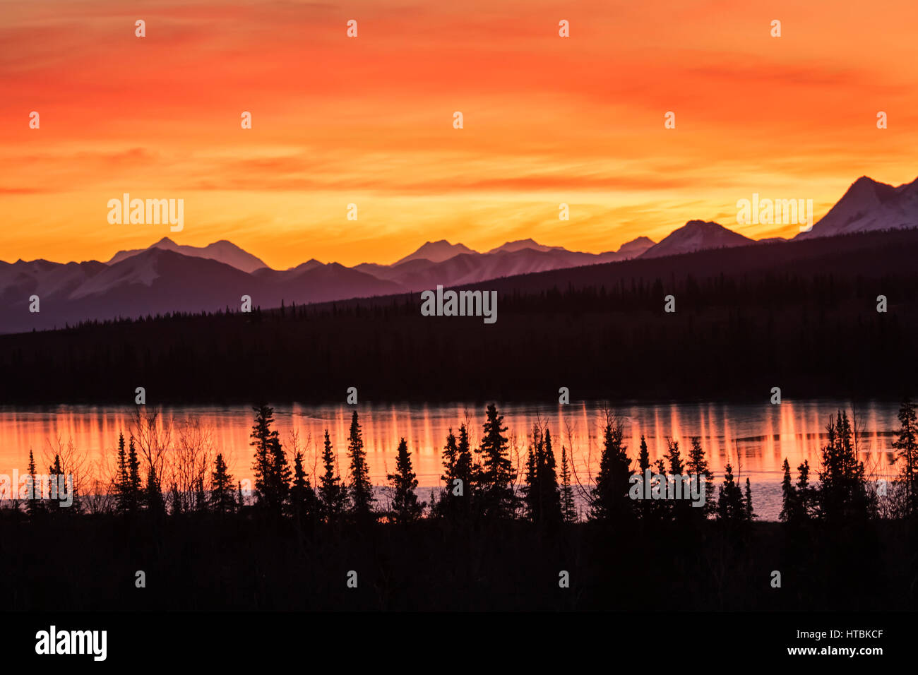 Clouds glowing at sunrise over a mountain range and lake, interior ...