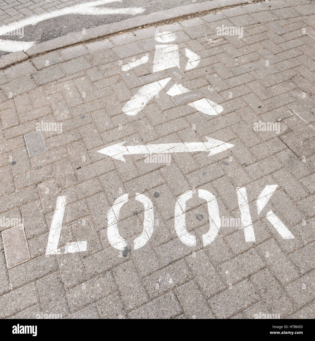 A look both ways sign with a stick figure person on a cobble stone ...