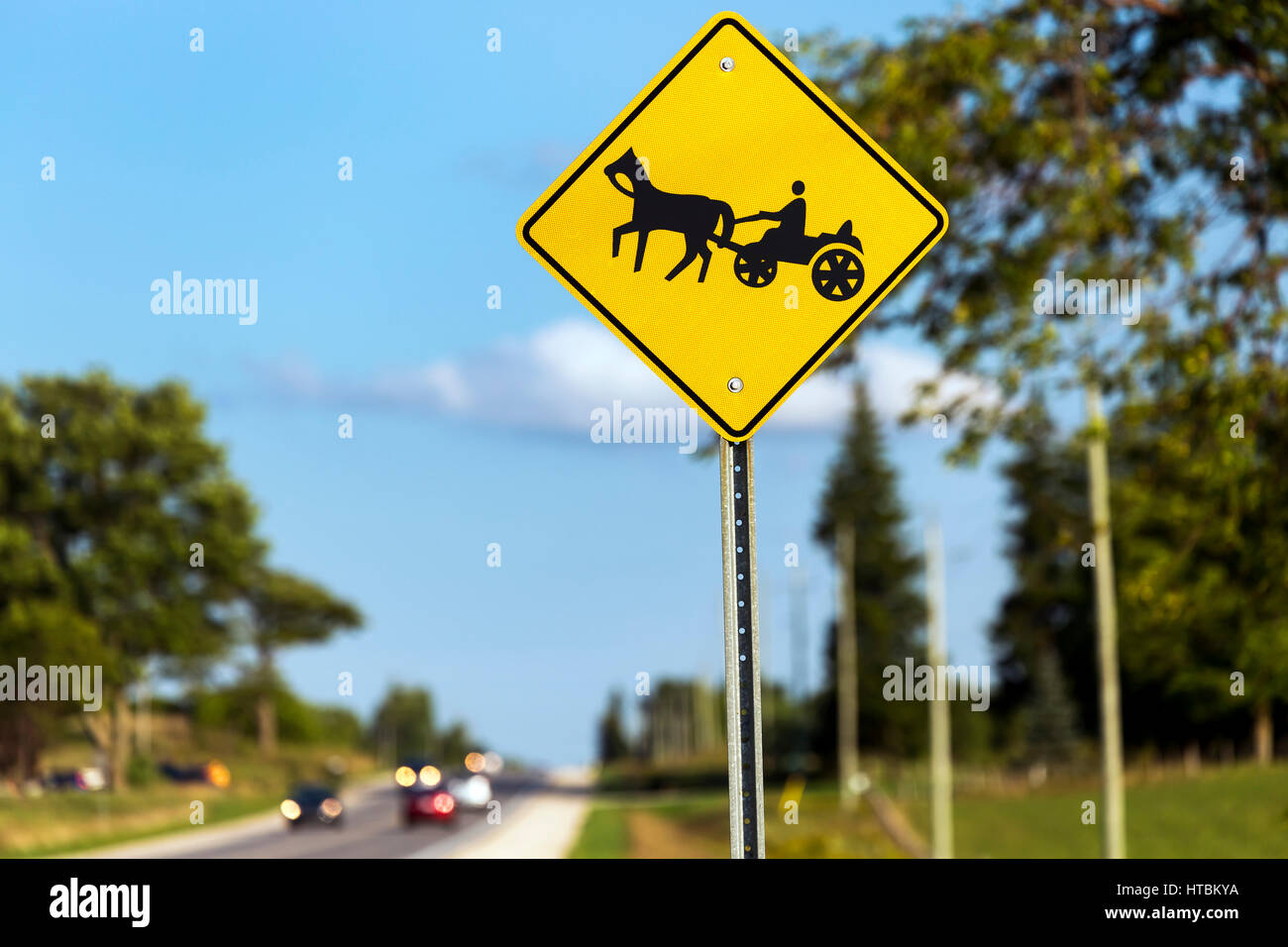 Road sign of horse and buggy along highway with cars in the background ...