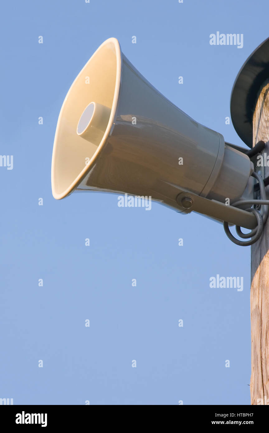 Gray plastic horn loudspeaker, wooden pole, over blue sky, vertical ...