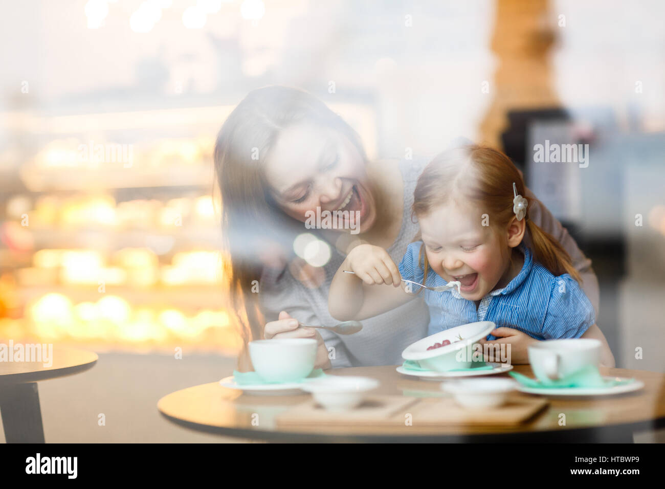 Cheerful mother and daughter having dessert Stock Photo - Alamy