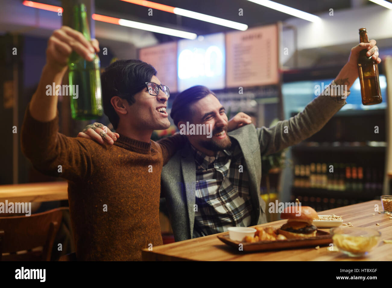 Ecstatic men with beer celebrating victory of football team Stock Photo ...