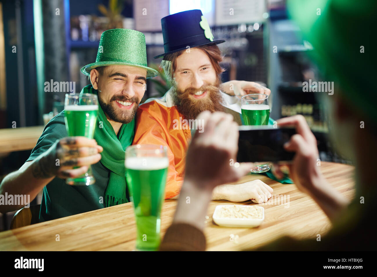 Happy guys with beer having been photographed by their friend in pub ...