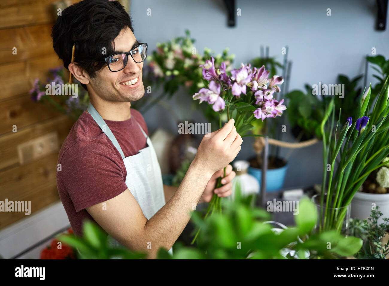 Handsome young man with flower working as florist Stock Photo - Alamy