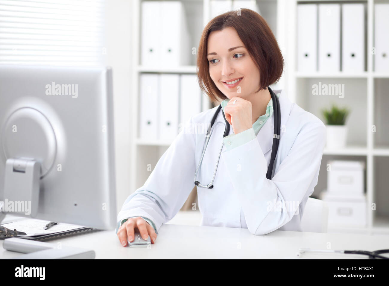 Young brunette female doctor sitting at a desk and working on the ...