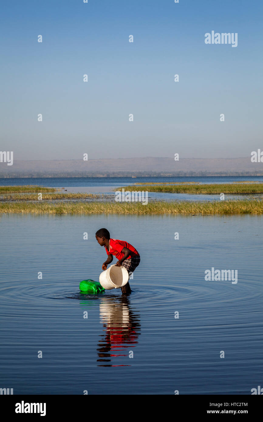 A Young Boy Collects Water From The Lake In A Bucket and Container ...