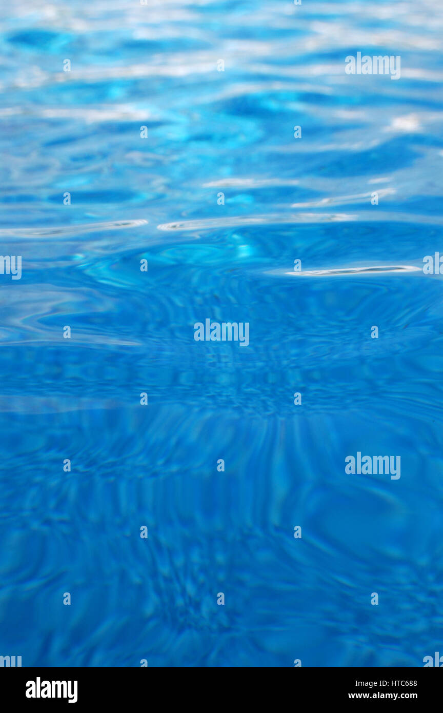 Late-afternoon sun reflecting off the surface an empty swimming pool ...